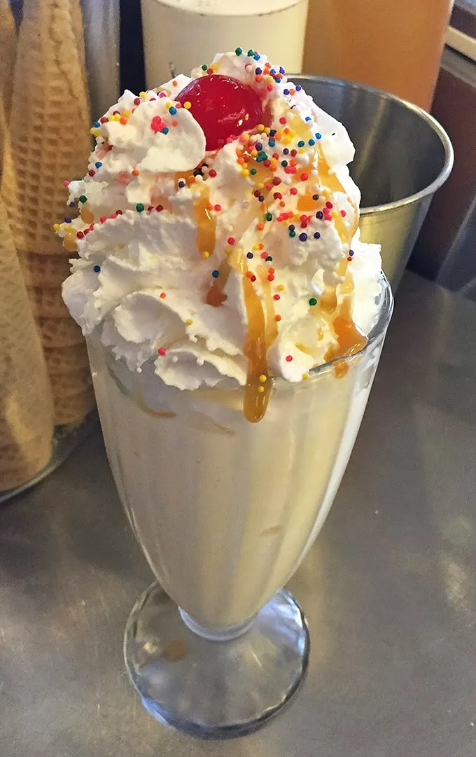 Holy moly, that's not a milkshake—it's a work of art! Topped with a mountain of whipped cream and a rainbow of sprinkles, this beauty is what dreams are made of.