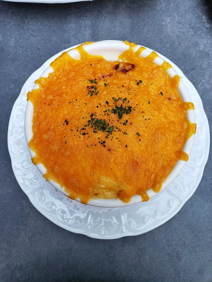 This mac and cheese doesn't just arrive at your table—it makes an entrance, with a golden top that crackles with anticipation.