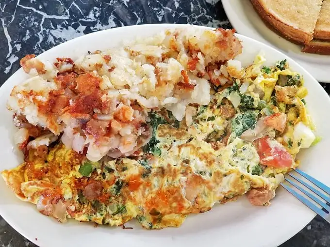 Not all heroes wear capes – some come on white plates with perfectly diced vegetables folded into fluffy eggs alongside crispy home fries.