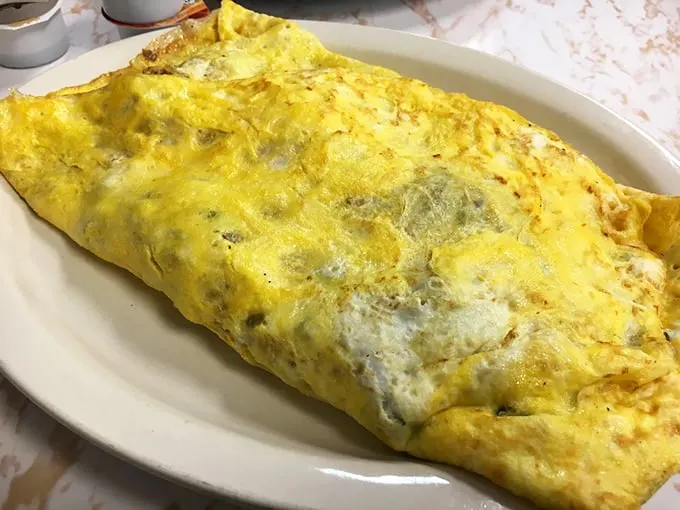 Behold, the golden chariot of breakfast! This omelet is so fluffy, it might just float away if not for its cheesy anchor.