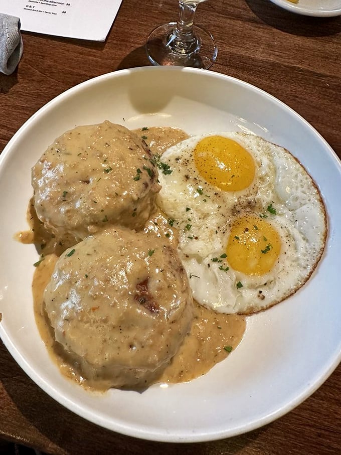 The breakfast trifecta: golden biscuits, creamy gravy, and sunny-side-up eggs. It's like a morning hug for your stomach.