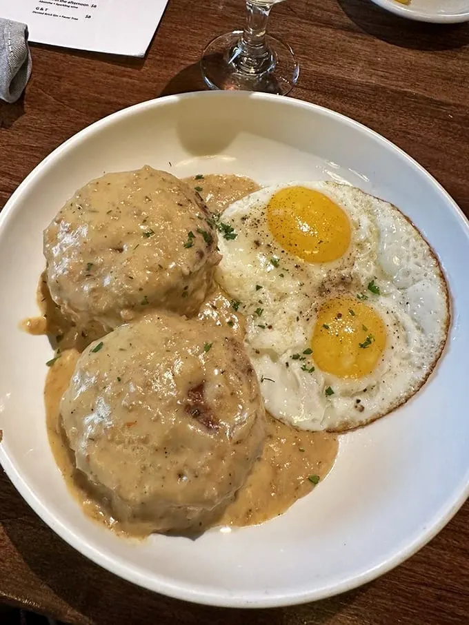 The breakfast trifecta: golden biscuits, creamy gravy, and sunny-side-up eggs. It's like a morning hug for your stomach.