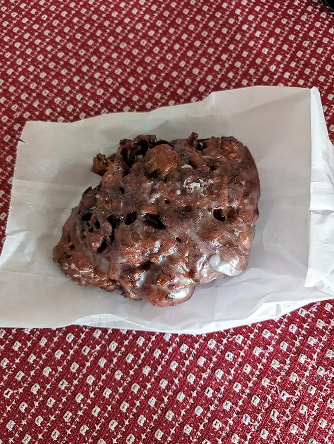 Behold the chocolate fritter in its natural habitat—wax paper. The irregular shape tells you it's handmade, and the glaze promises it's worth every calorie.