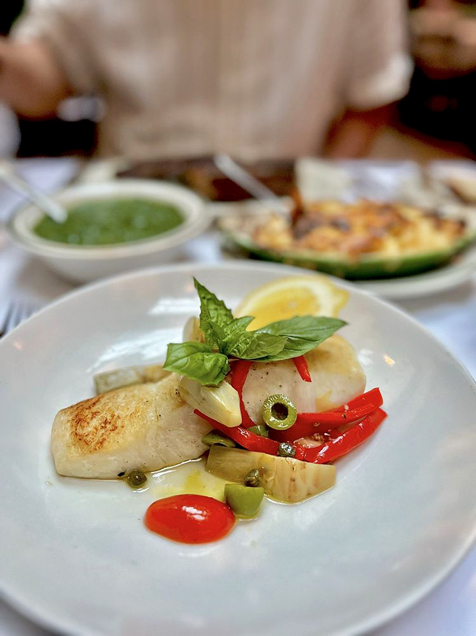 Even seafood gets the royal treatment—this halibut's delicate flesh contrasts with vibrant peppers and olives in a Mediterranean love letter.
