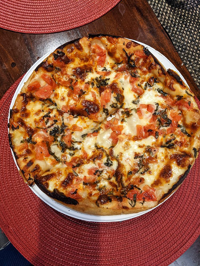 Margherita magic! Fresh tomatoes and basil play hide-and-seek with melted mozzarella, creating a pizza that's basically a portable Italian vacation.