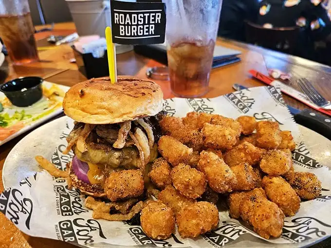 The Roadster Burger arrives with its own flag, as if claiming new territory in the land of serious sandwiches. Those tater tots? Crispy little bonus rounds.