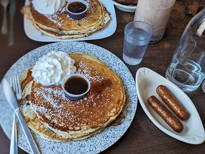 These pancakes aren't just round—they're discs of joy, their golden surfaces collecting maple syrup in tiny pools of breakfast bliss.