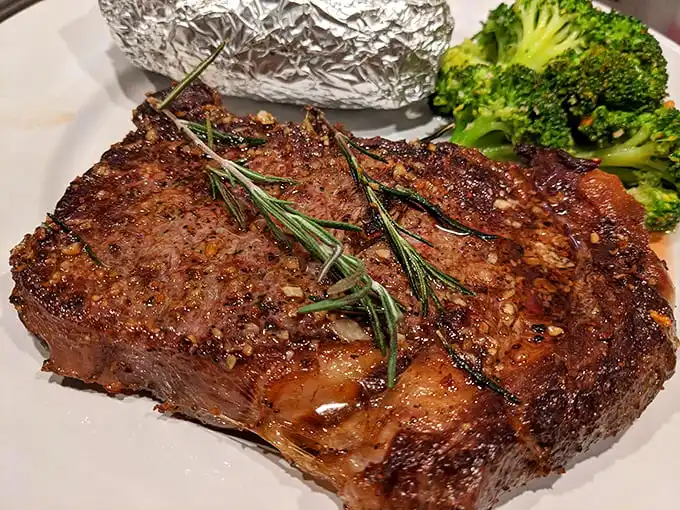 A steak that doesn't need a filter or fancy lighting—just your undivided attention. The rosemary sprigs aren't just garnish; they're aromatic messengers of what's to come.