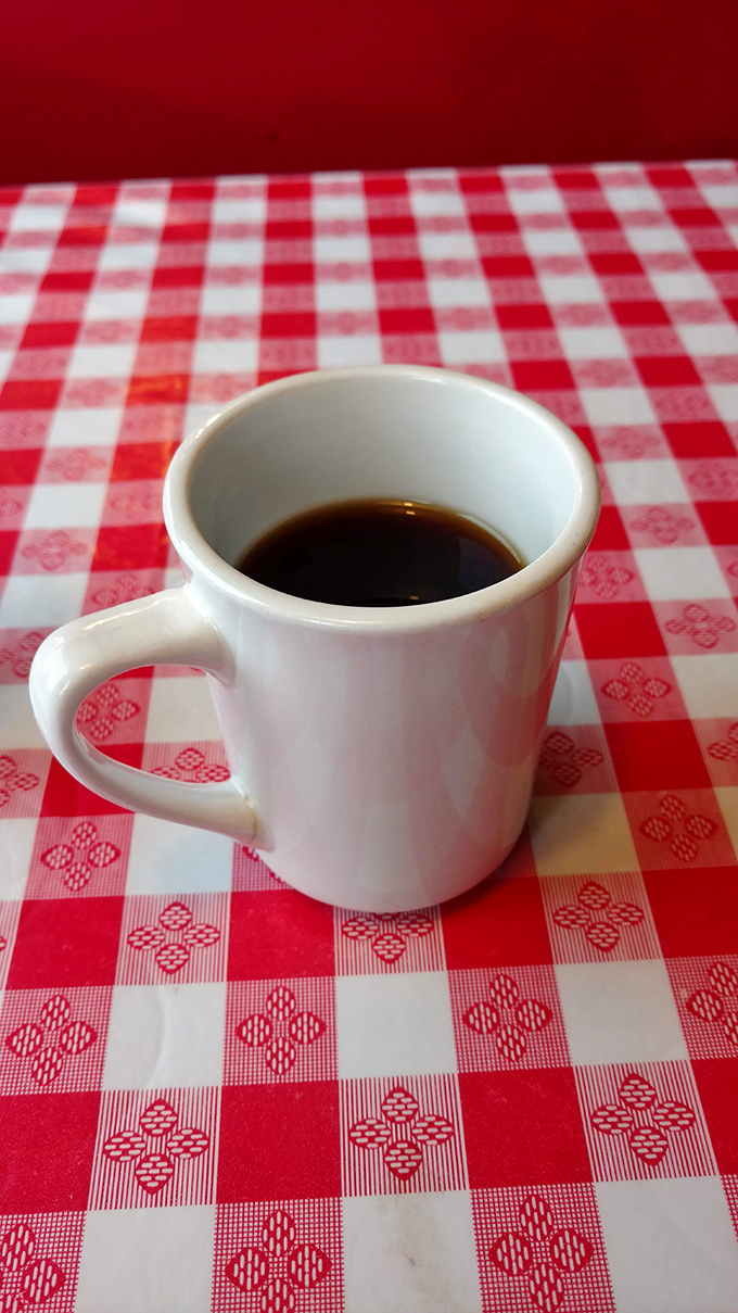 Simple pleasures: Hot diner coffee in a sturdy white mug on a checkered tablecloth. No foam art needed when the coffee speaks for itself.