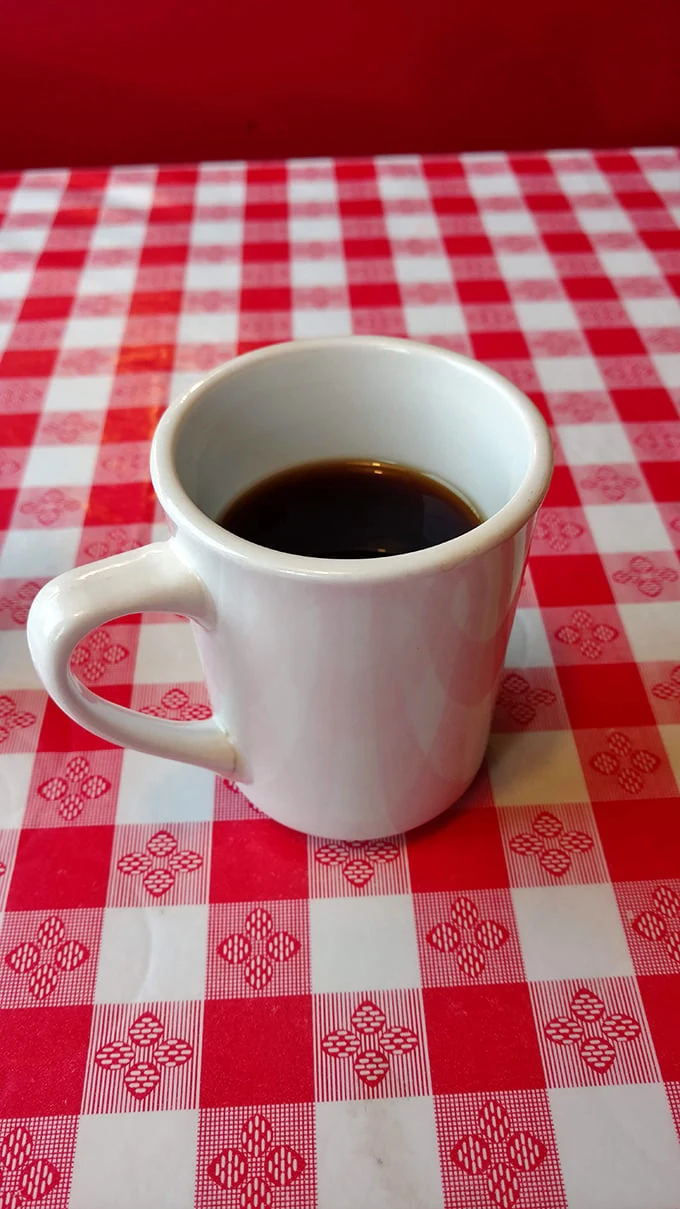 Simple pleasures: Hot diner coffee in a sturdy white mug on a checkered tablecloth. No foam art needed when the coffee speaks for itself.