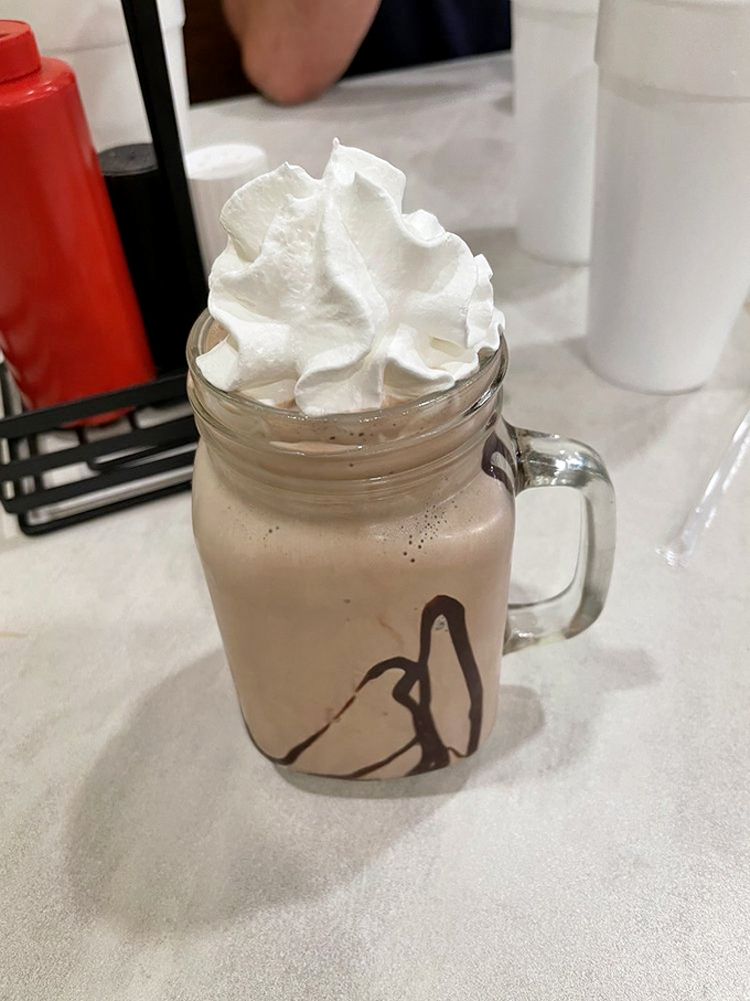 A chocolate shake served in a mason jar with whipped cream that defies gravity—proof that sometimes the best desserts don't need a passport.