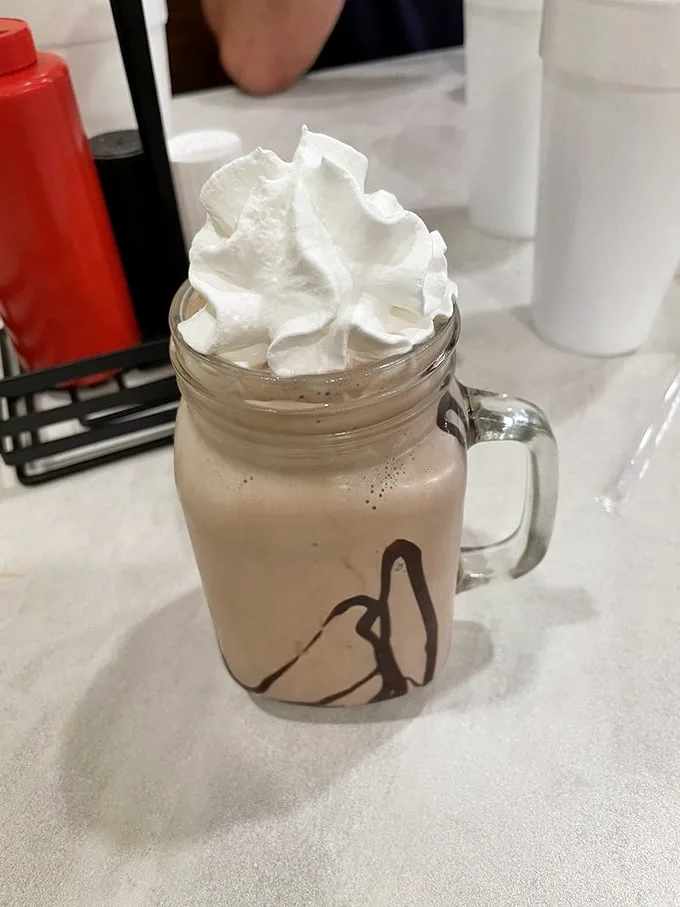 A chocolate shake served in a mason jar with whipped cream that defies gravity—proof that sometimes the best desserts don't need a passport.