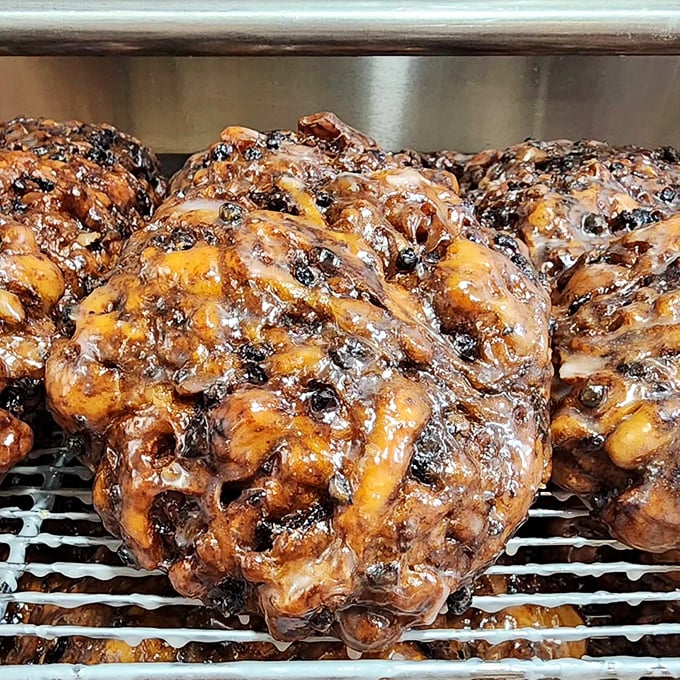 Fresh apple fritters cooling on the rack—the donut equivalent of front-row concert tickets. Worth setting your alarm for 5 AM.