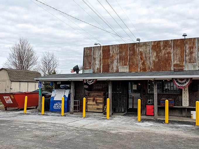 The weathered exterior of Rusted Silo isn't just authentic—it's a time machine disguised as a barbecue joint. Those yellow posts aren't just practical; they're exclamation points announcing culinary treasure.