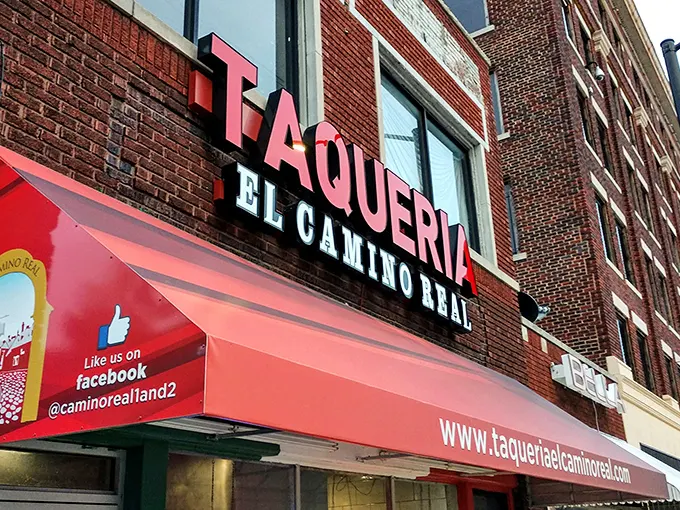 The glowing red "TAQUERIA" sign against brick isn't just signage—it's a beacon of hope for hungry souls seeking authentic Mexican flavors in Kansas City.