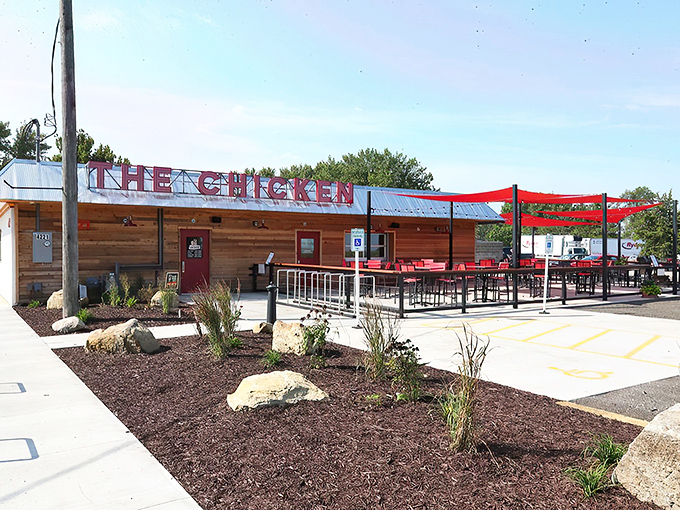 The rustic wooden exterior with those eye-catching red shade sails isn't just inviting—it's practically shouting "Come get some chicken that'll change your life!"