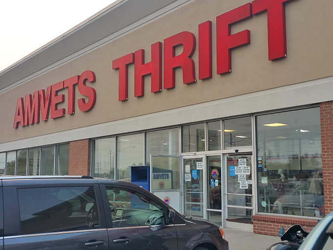 The bright red letters of AMVETS Thrift call to bargain hunters like a beacon, promising treasures waiting just beyond those doors.