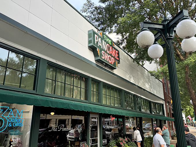 The iconic green awning and vintage sign of The Pancake Shop stands as a breakfast beacon on Hot Springs' Central Avenue, promising morning magic within.