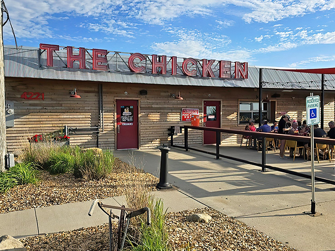 The rustic wooden exterior with those eye-catching red shade sails isn't just inviting—it's practically shouting "Come get some chicken that'll change your life!"