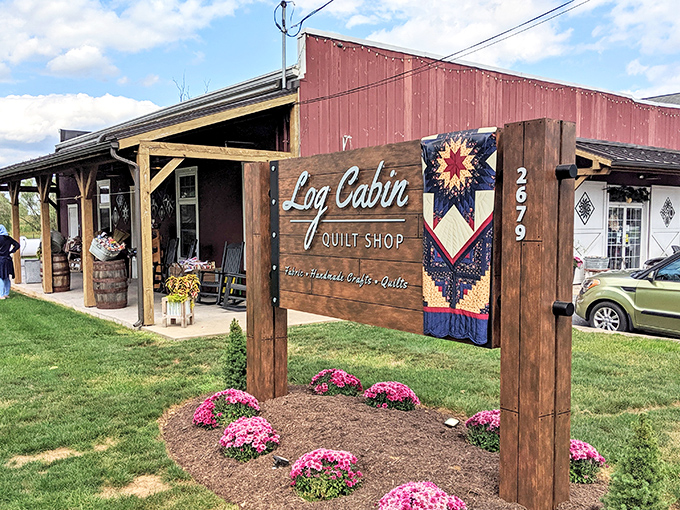 The iconic red barn exterior of Log Cabin Quilt Shop welcomes fabric enthusiasts with its charming quilt block emblem—a colorful beacon for crafters in Amish Country.