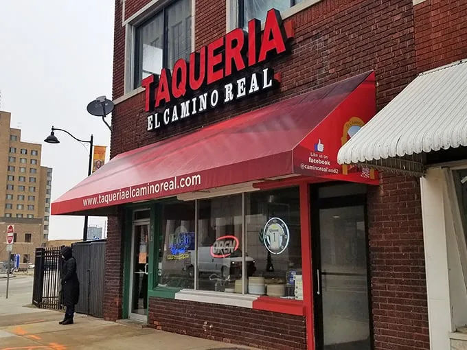 The glowing red "TAQUERIA" sign against brick isn't just signage—it's a beacon of hope for hungry souls seeking authentic Mexican flavors in Kansas City.
