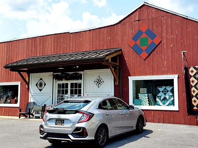 The iconic red barn exterior of Log Cabin Quilt Shop welcomes fabric enthusiasts with its charming quilt block emblem—a colorful beacon for crafters in Amish Country.