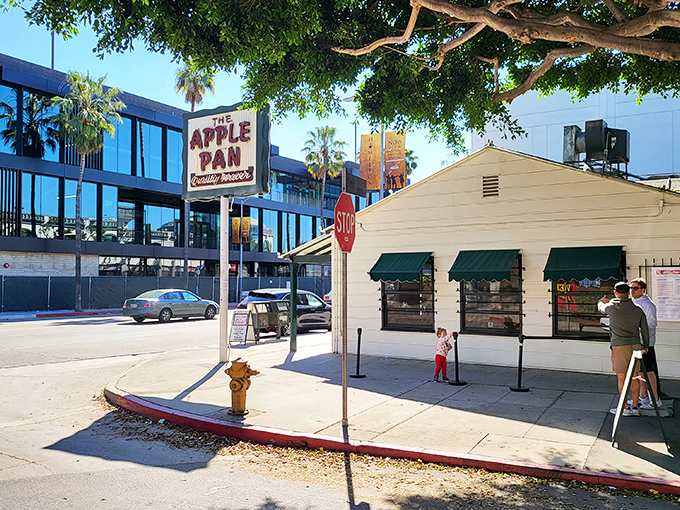 The unassuming white exterior of The Apple Pan stands like a time capsule on Pico Boulevard, its iconic sign promising "Quality Forever" beneath LA's blue skies.