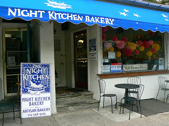 The blue awning beckons like a dessert lighthouse guiding sweet-toothed sailors home. Chestnut Hill's charming Night Kitchen Bakery promises delicious adventures ahead.