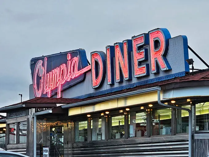 That neon sign isn't just advertising—it's a time machine. The Olympia's iconic blue and pink glow has been guiding hungry travelers home since Eisenhower was president.