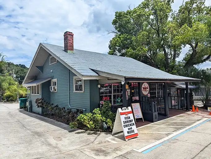 Tony's charming exterior beckons seafood lovers with its weathered gray siding and cheerful red umbrellas—like a New England fishing shack that somehow drifted down to Florida.