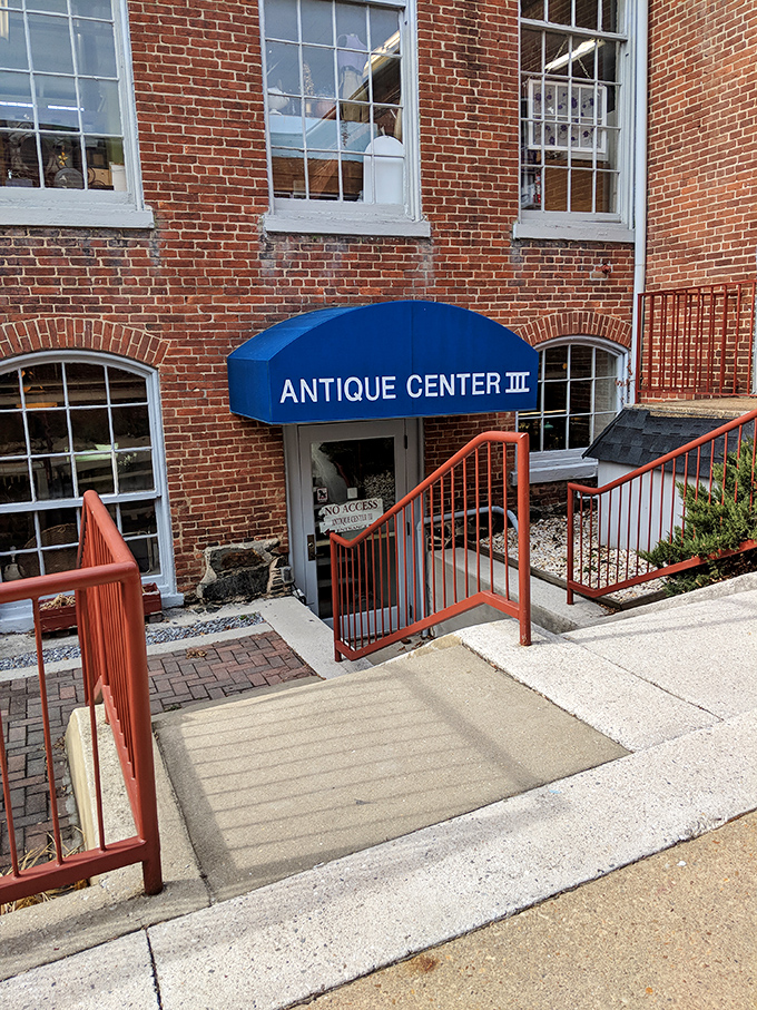 The historic brick exterior of Savage Mill welcomes treasure hunters with its distinctive blue awning—industrial architecture transformed into an antiquing paradise.