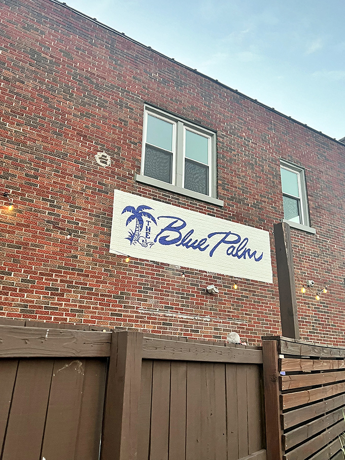 From the outside, The Blue Palm plays it cool – a modest brick building that keeps its tropical treasures hidden like a speakeasy with sunscreen.