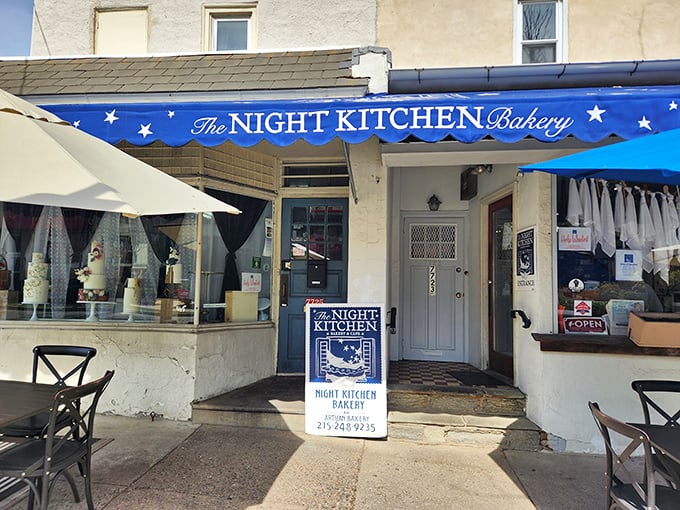 The blue awning beckons like a dessert lighthouse guiding sweet-toothed sailors home. Chestnut Hill's charming Night Kitchen Bakery promises delicious adventures ahead.