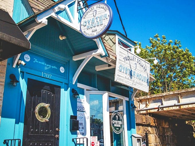 The blue façade of Trolley Square Oyster House stands like a maritime beacon in Wilmington, promising seafood treasures within those weathered wooden signs.