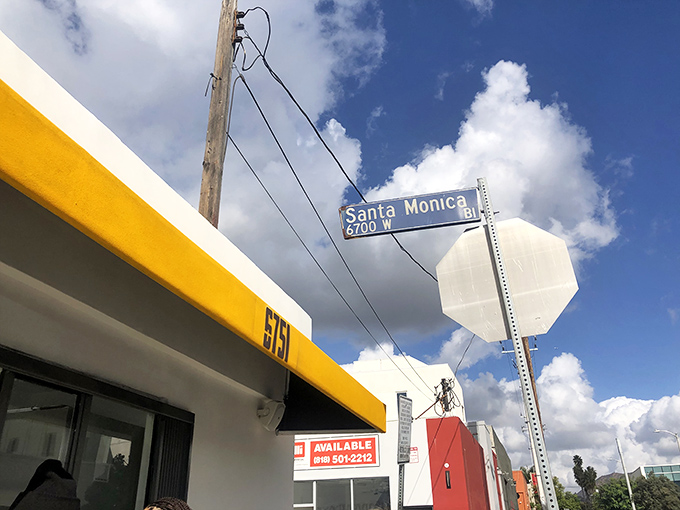 The corner of Santa Monica Boulevard where breakfast dreams come true. That yellow awning is like a culinary lighthouse guiding hungry souls to sandwich salvation.