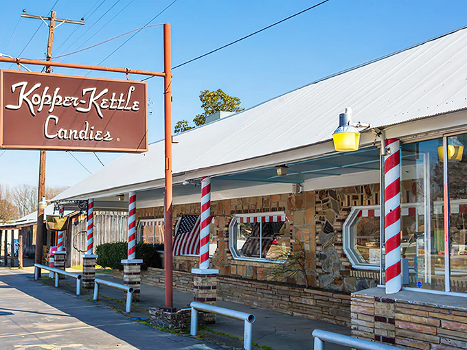 The iconic storefront of Kopper Kettle Candies stands resilient against Arkansas rain, its candy-striped poles promising sweet refuge from ordinary life.