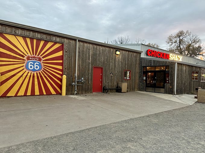 The humble wooden exterior of Chicken Shack stands proudly against an Oklahoma sky, its bold red and yellow sign promising poultry perfection inside.