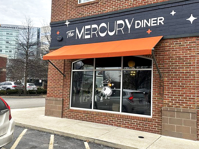 The Mercury Diner's navy blue facade with bright orange awning isn't just inviting—it's practically a bat signal for hungry Ohioans seeking comfort food nirvana.