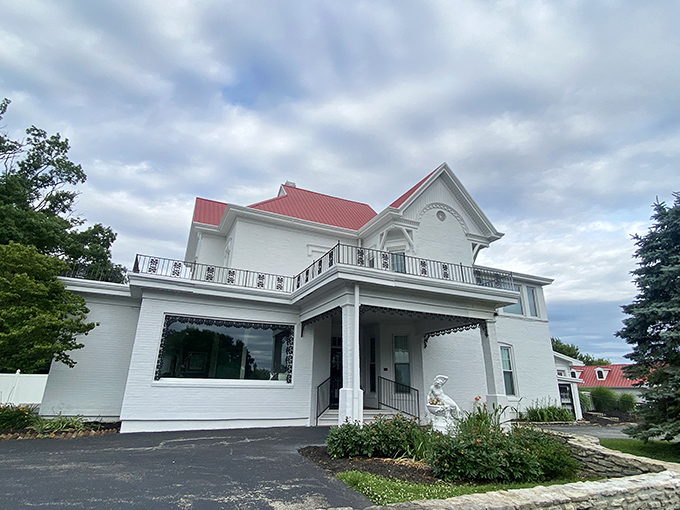 The white colonial mansion with its distinctive red roof stands as a beacon of Southern hospitality, promising culinary treasures within its historic walls.