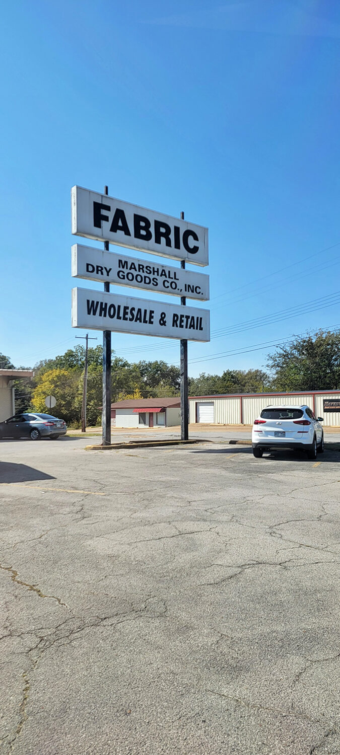 The sign says "FABRIC" with the subtlety of a Broadway marquee. No false advertising here—just a promise of textile treasures awaiting inside.