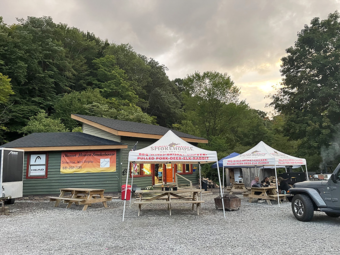 The green cabin nestled against West Virginia's lush forest backdrop isn't just a smokehouse—it's a portal to flavor country. Picnic tables await your food coma.