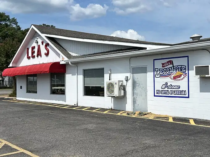 The iconic white building with bold red "LEA'S" lettering and matching awning stands as a beacon for hungry travelers – a Louisiana landmark since 1928.