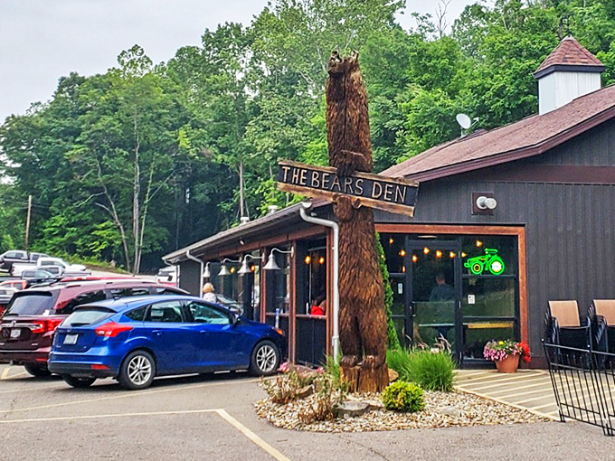 The rustic cabin exterior of Bear's Den Steakhouse promises a wilderness experience with gourmet credentials. That wooden bear statue isn't just decoration—it's a preview of coming attractions.