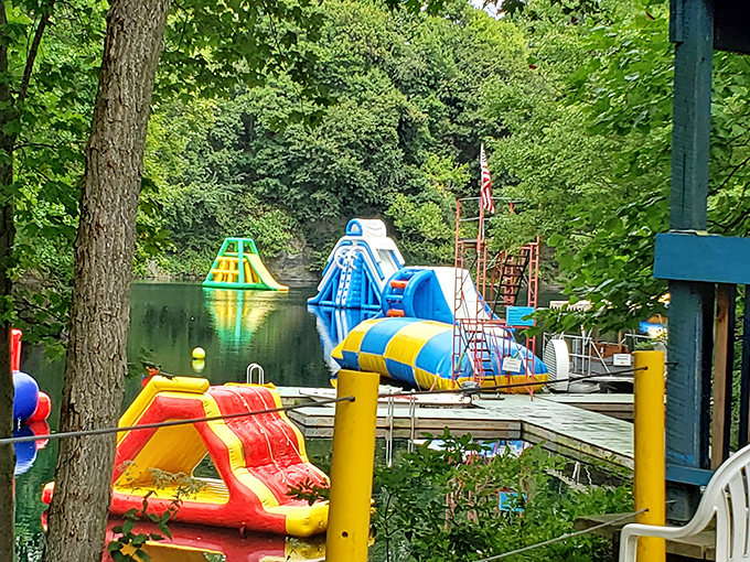 Where the magic happens! Colorful inflatable obstacles float invitingly on crystal-clear quarry waters, promising adventures that'll make your inner child high-five your actual children.