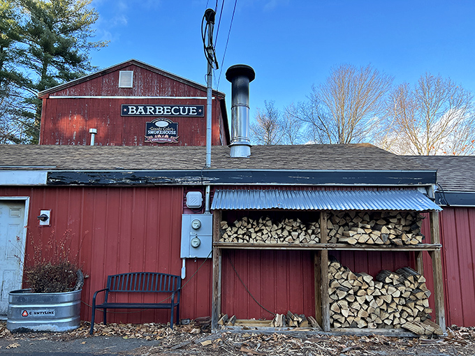 The weathered red barn exterior isn't just rustic charm—it's a smoke signal to BBQ pilgrims that authentic flavor awaits inside this New Hampshire treasure.