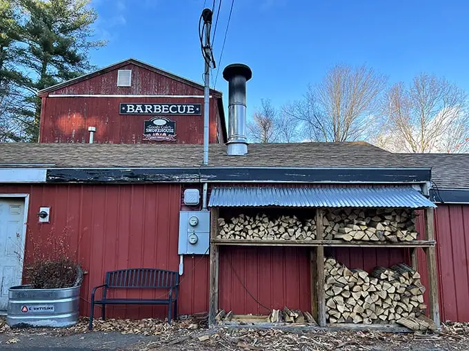 The weathered red barn exterior isn't just rustic charm—it's a smoke signal to BBQ pilgrims that authentic flavor awaits inside this New Hampshire treasure.
