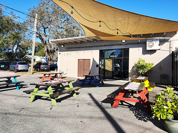 Colorful picnic tables under tan shade sails create an inviting oasis where carb-lovers gather like pilgrims at a delicious shrine.