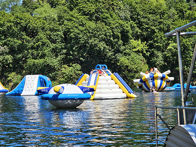 Where the magic happens! Colorful inflatable obstacles float invitingly on crystal-clear quarry waters, promising adventures that'll make your inner child high-five your actual children.