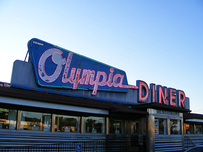 That neon sign isn't just advertising—it's a time machine. The Olympia's iconic blue and pink glow has been guiding hungry travelers home since Eisenhower was president.