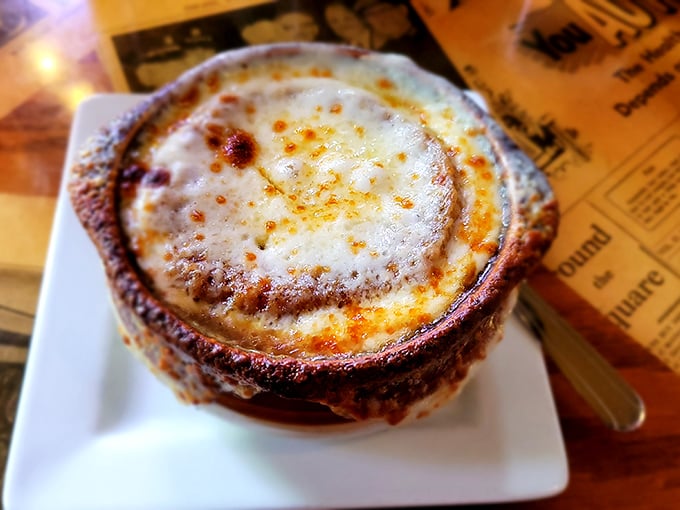 French onion soup that's had a proper education—deeply flavored broth supporting a golden, bubbling cheese roof that demands to be broken into. 
